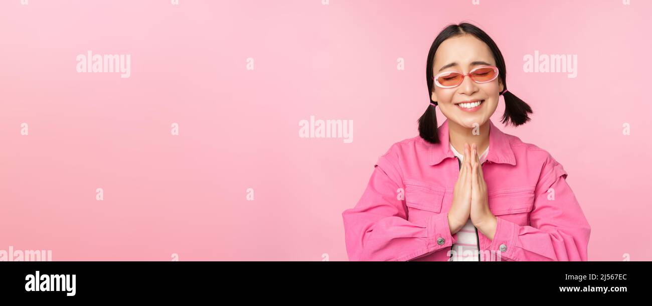 Please. Cute asian girl asking favour, begging, standing against studio ...