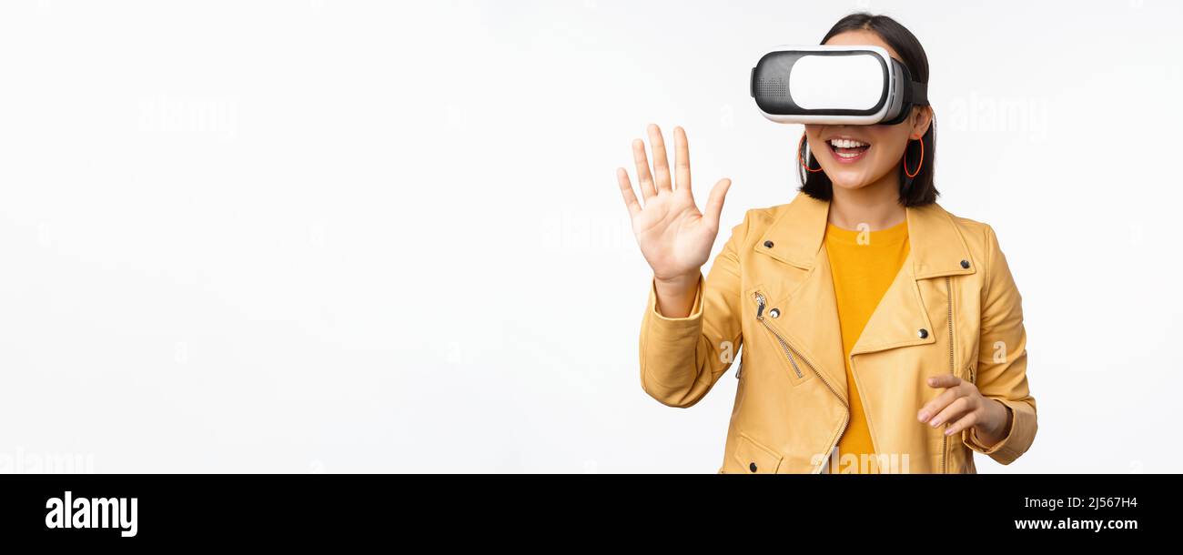 Happy asian girl in VR headset, saying hello in virtual reality chat ...