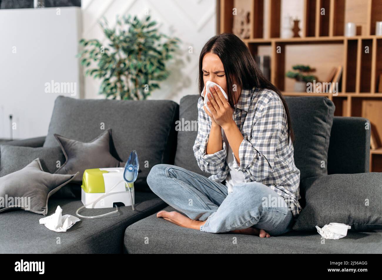 Sick caucasian brunette girl sit on couch at home, feel unhealthy, she ...