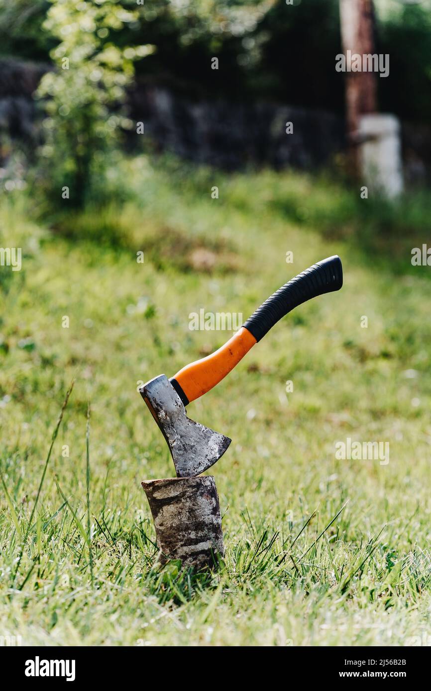 Axe with orange handle sticks out in hemp against the background of ...