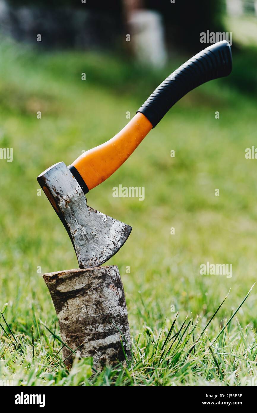 Axe with orange handle sticks out in hemp against the green grass Stock ...