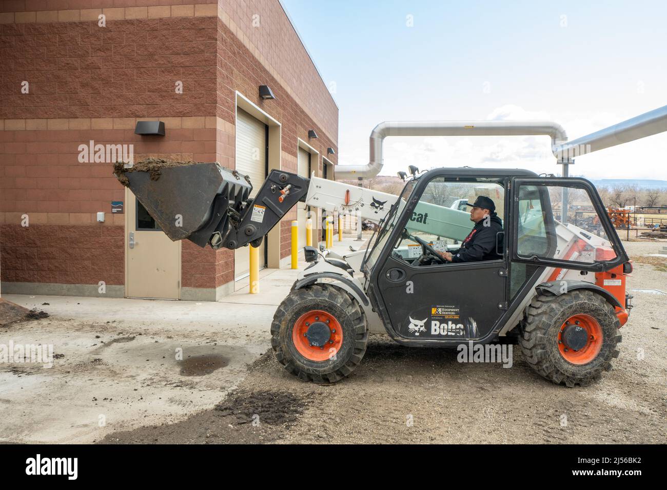 An operator moves dewatered sludge with a front-end loader in an SBR or ...