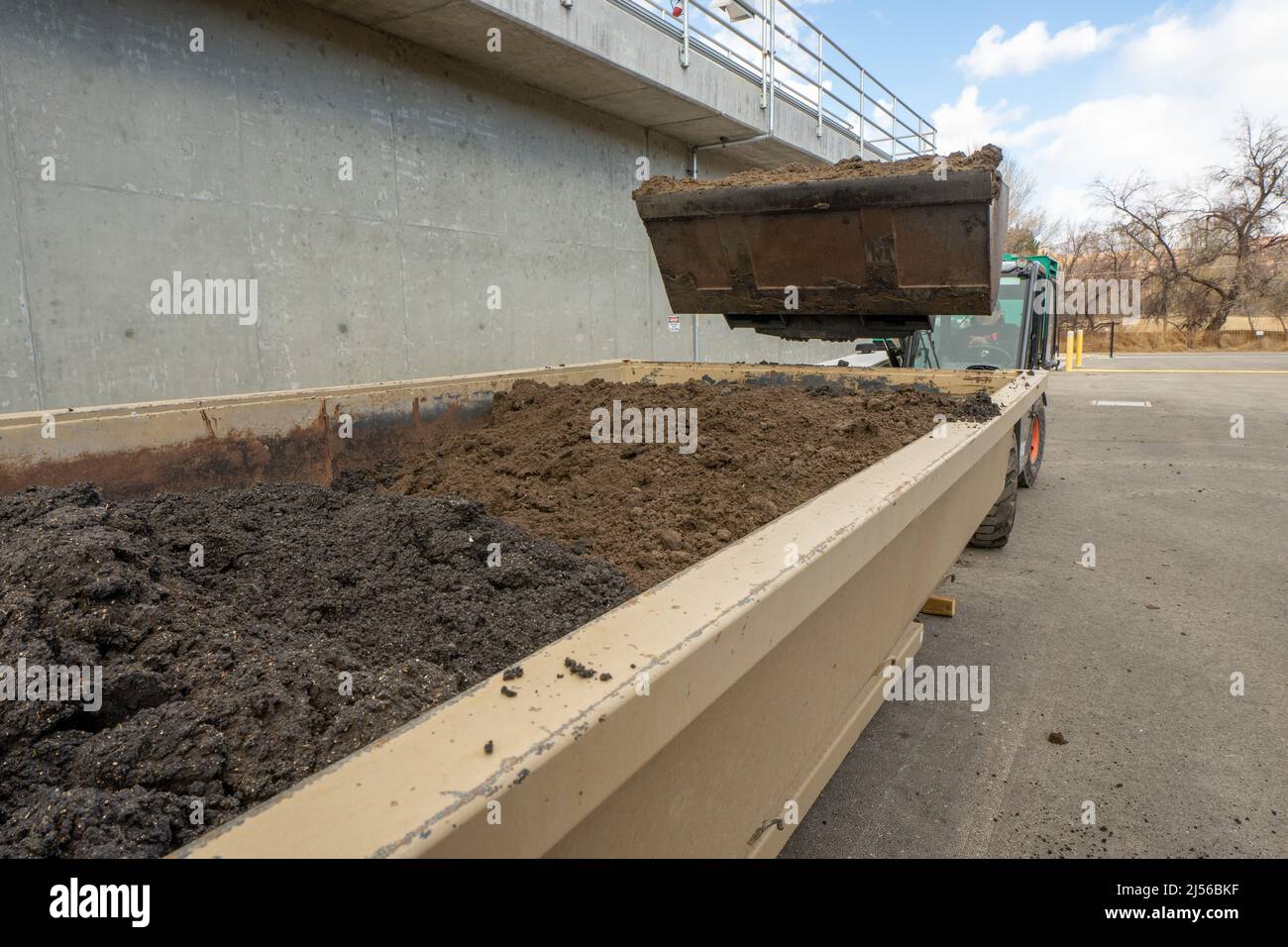 An operator moves dewatered sludge with a front-end loader in an SBR or ...