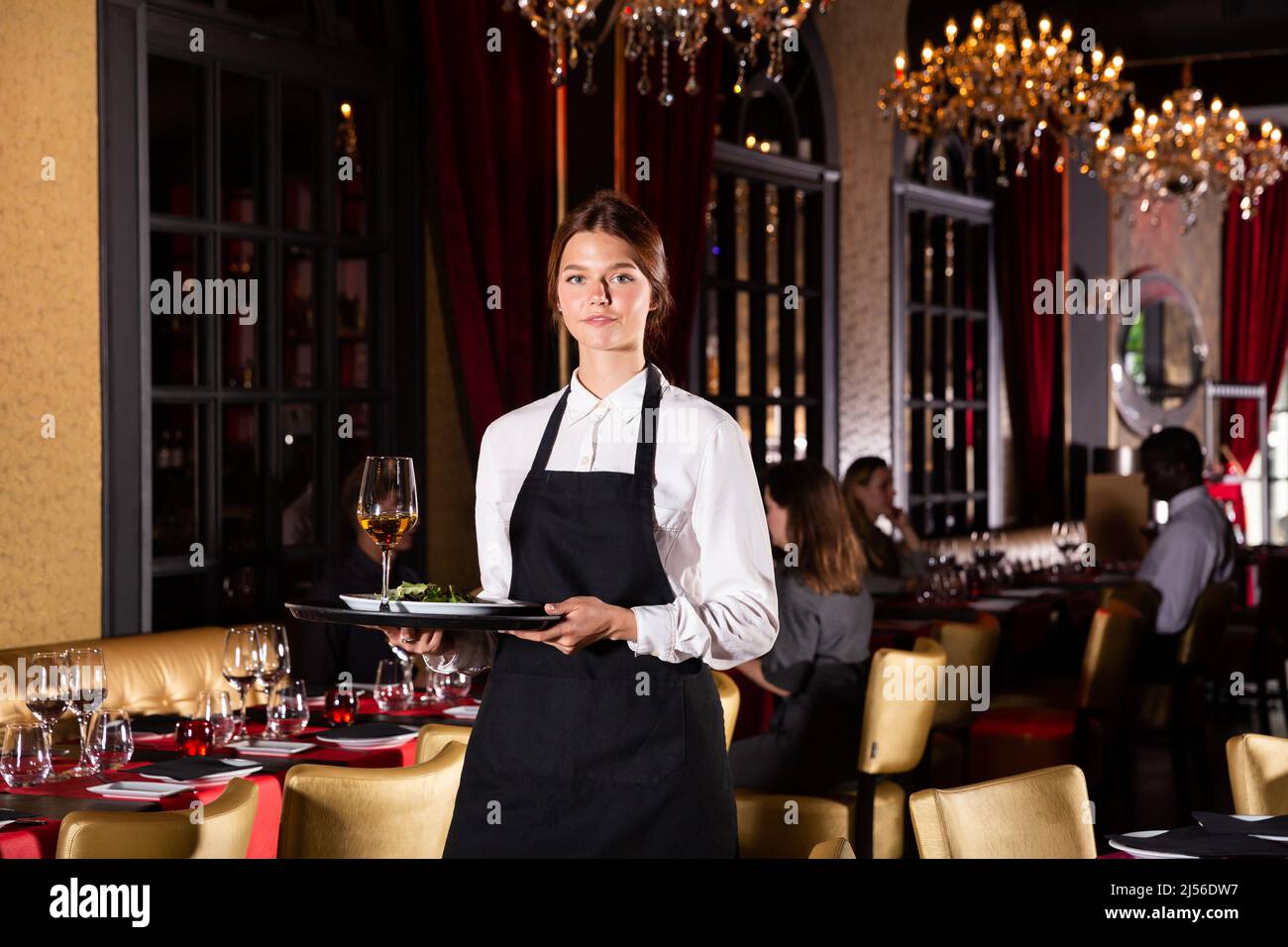 Female waiter standing with serving tray, recommending dishes in ...