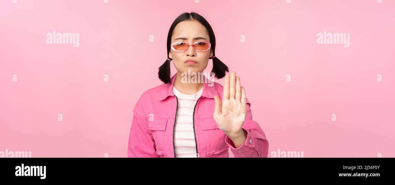 Image of serious, stylish asian girl in sunglasses, showing stop ...