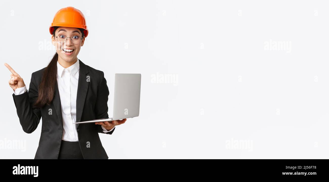 Excited happy asian female engineer, industrial woman in safety helmet ...