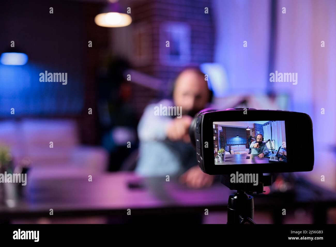 Content creator using camera to record podcast show in filming studio ...