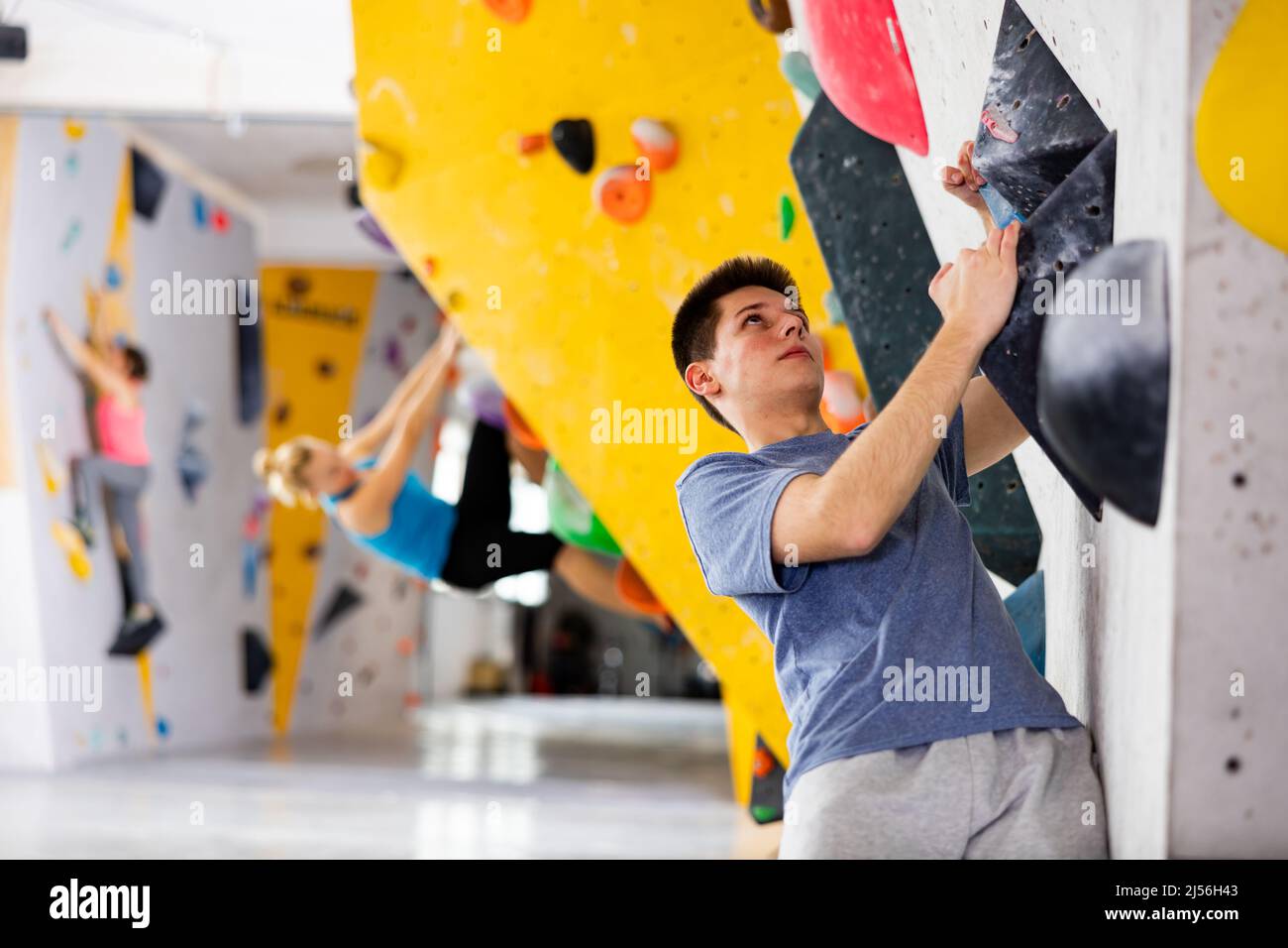 Male mountaineer climbing artificial rock wall without his belay ...