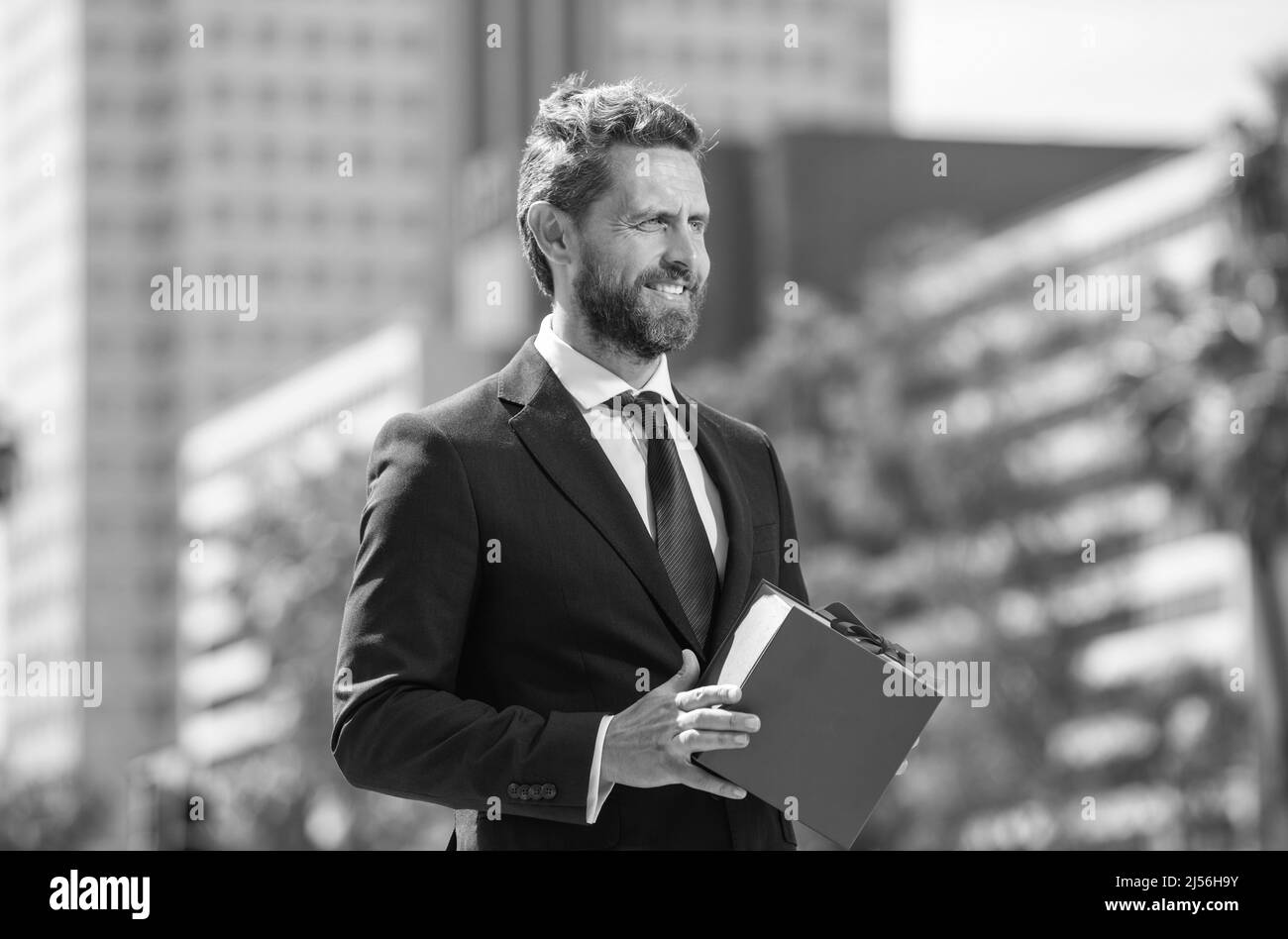 happy successful businessman in suit hold present box standing outdoor ...