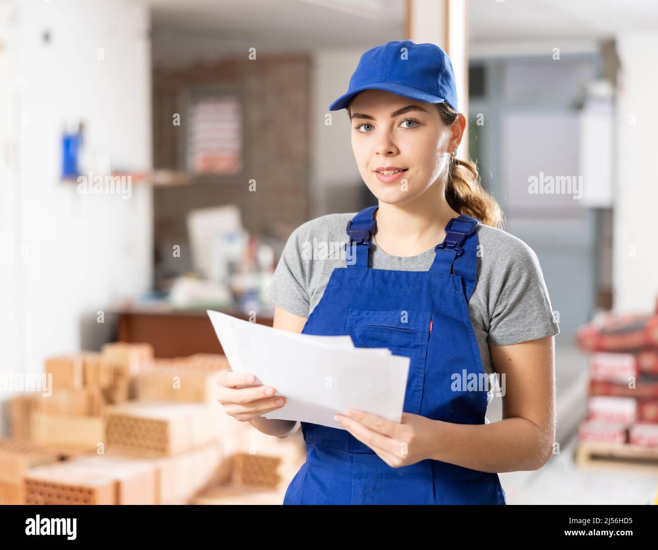 Female contractor checking blueprints and taking notes at building site ...