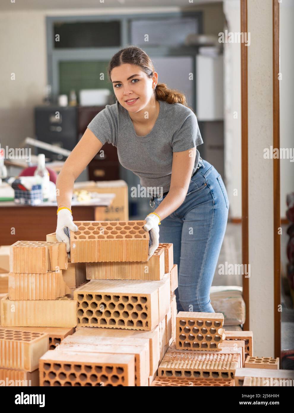 Girl stacking red bricks in her apartment during renovations Stock ...