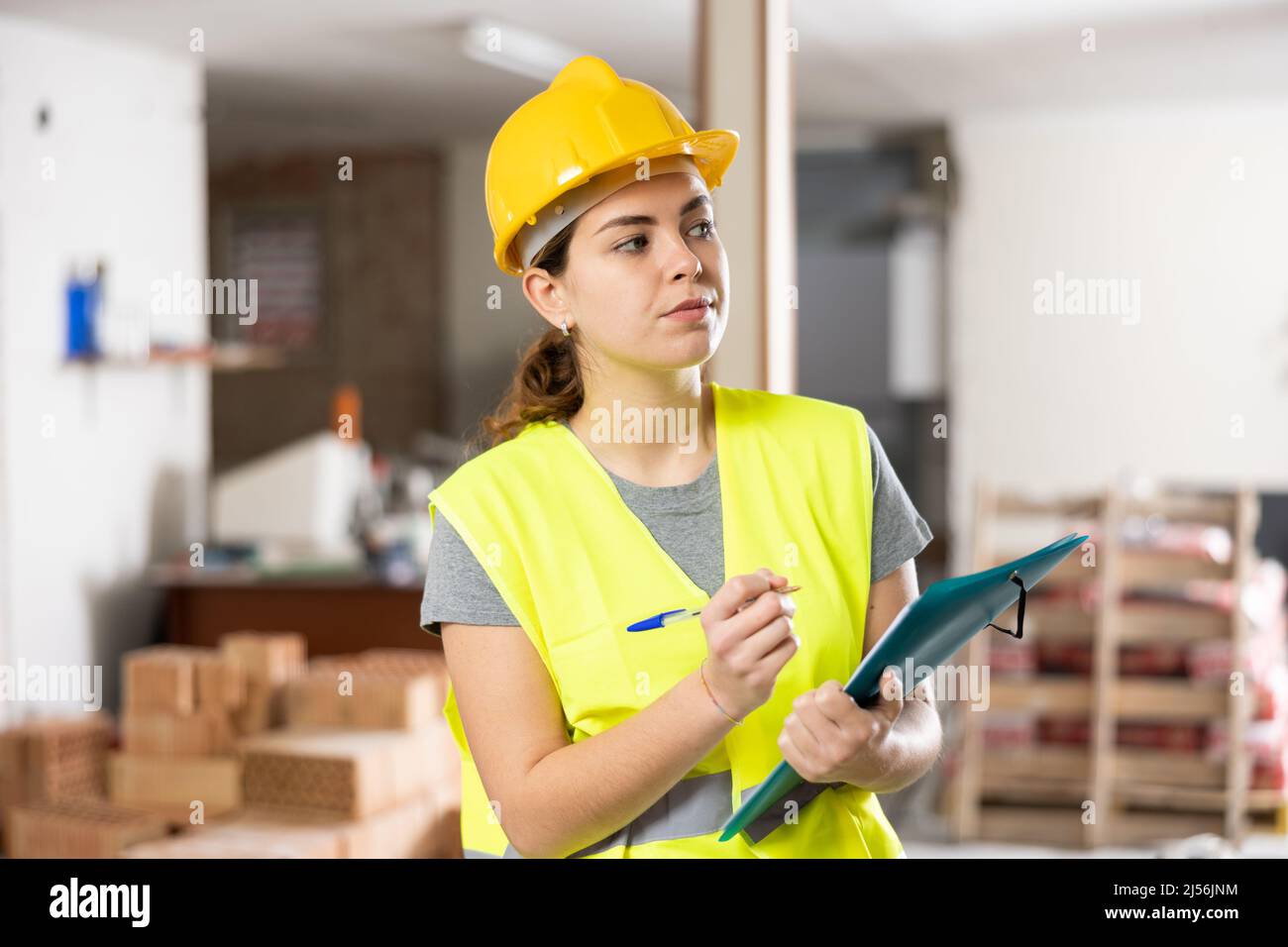 Female civil engineer making notes while controlling construction site ...