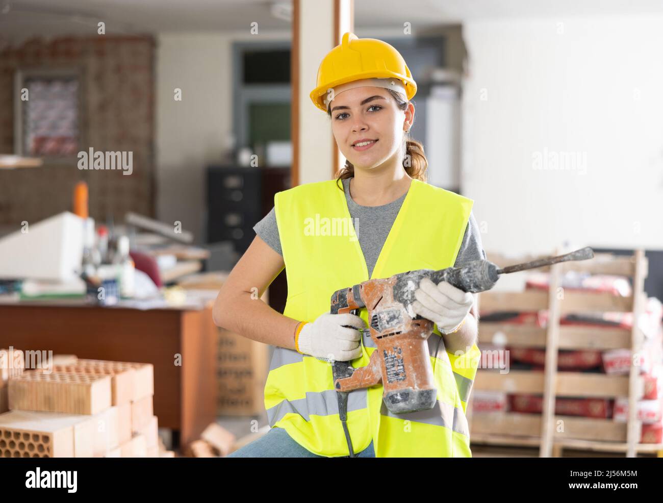 Female civil engineer holding pneumatic chipping hammer at construction ...