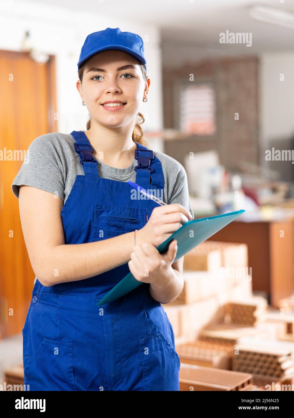 Female contractor checking blueprints and taking notes at building site ...