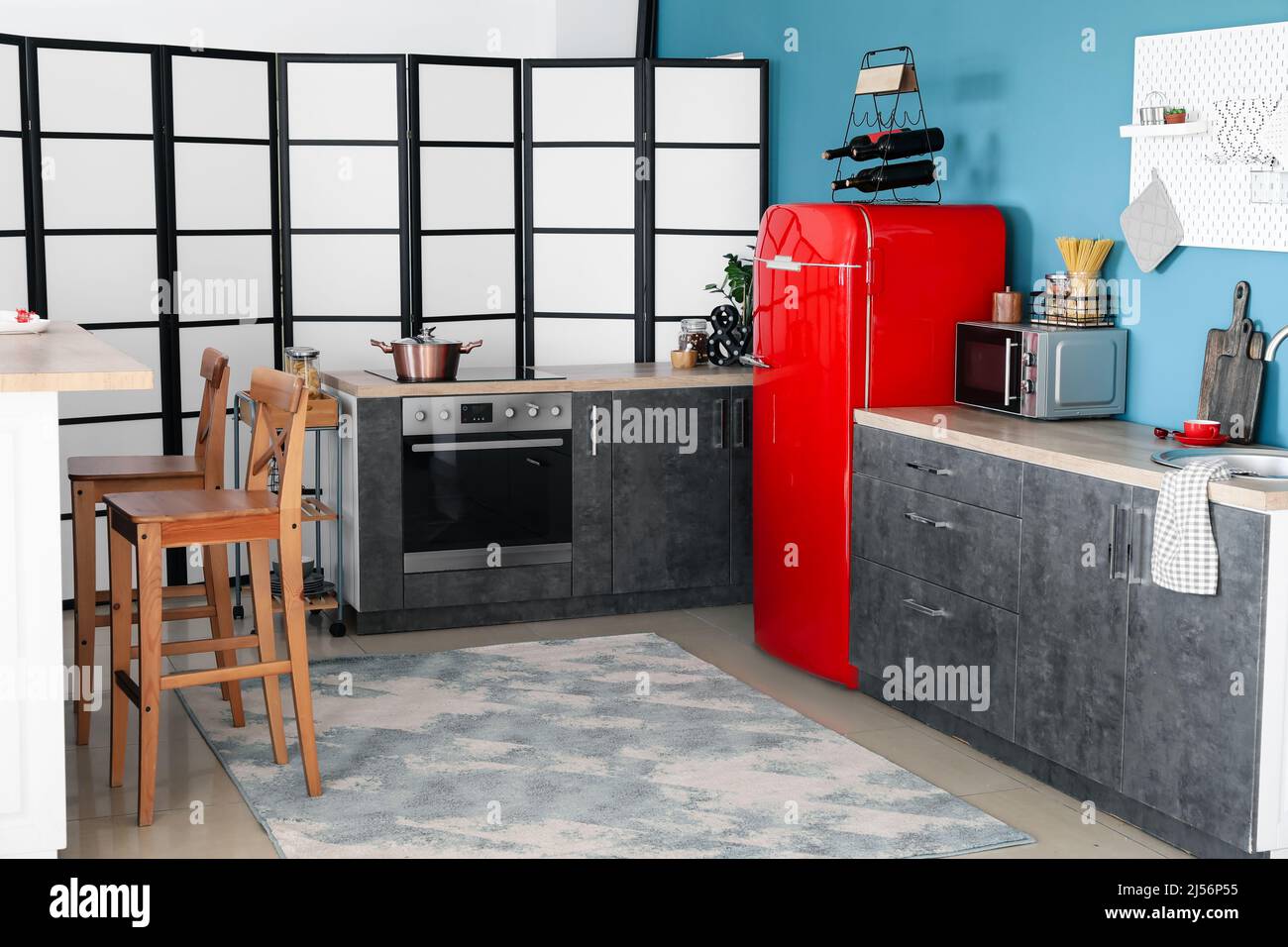 Interior of stylish kitchen with red fridge, counters and folding ...