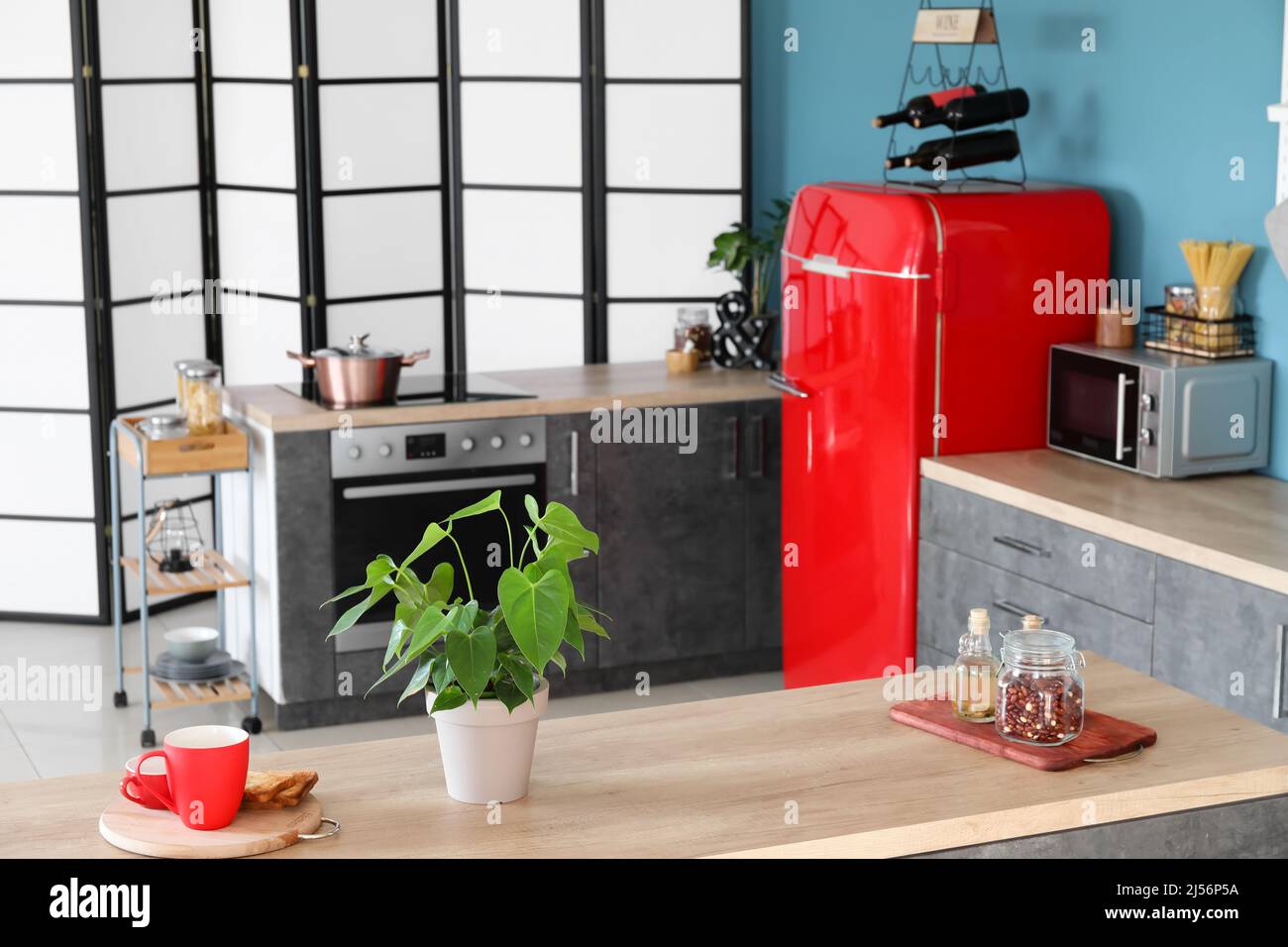 Interior of stylish kitchen with red fridge, counters and folding ...