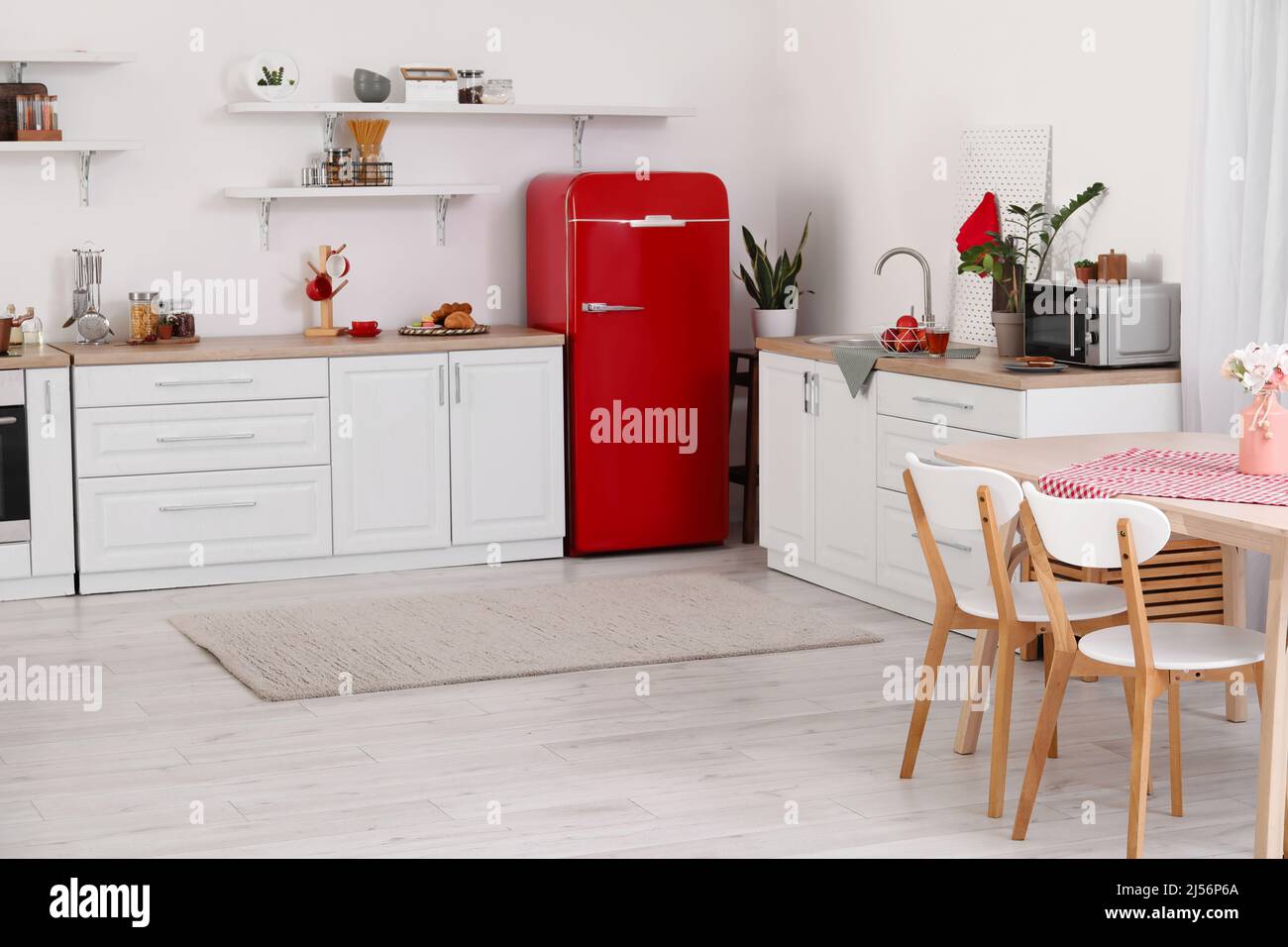 Interior of light kitchen with red fridge, counters and dining table ...