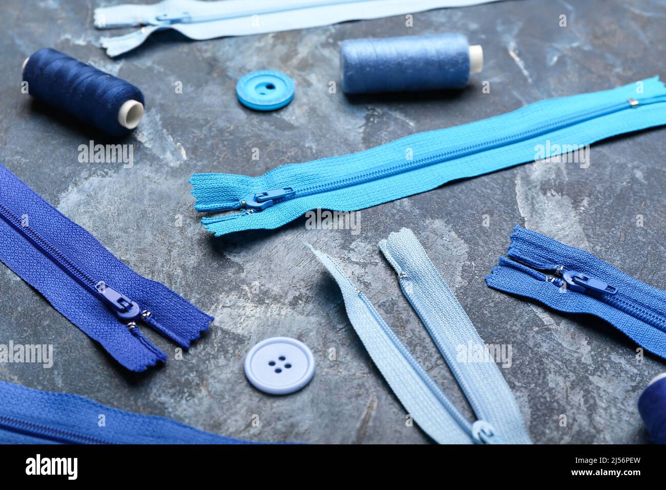 Stylish blue zippers, threads and buttons on blue grunge background ...
