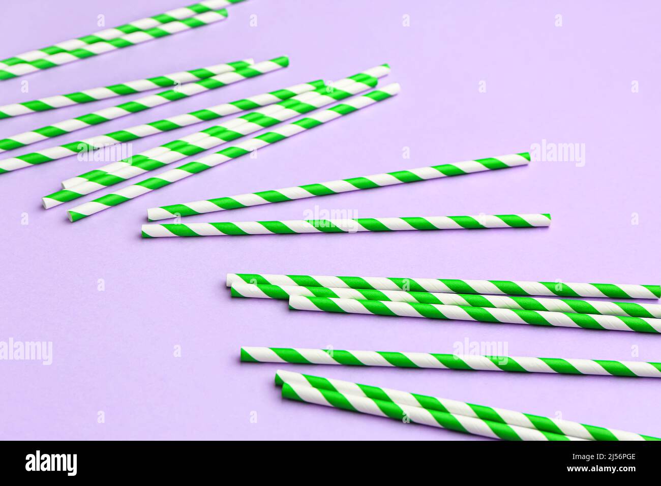 Stylish straws for drinks on purple background Stock Photo - Alamy