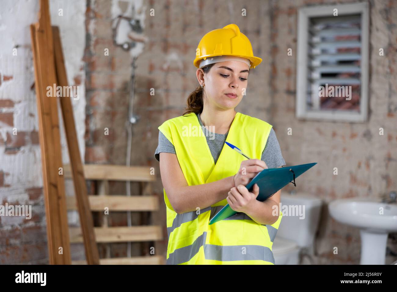Woman taking notes on indoor construction site Stock Photo - Alamy