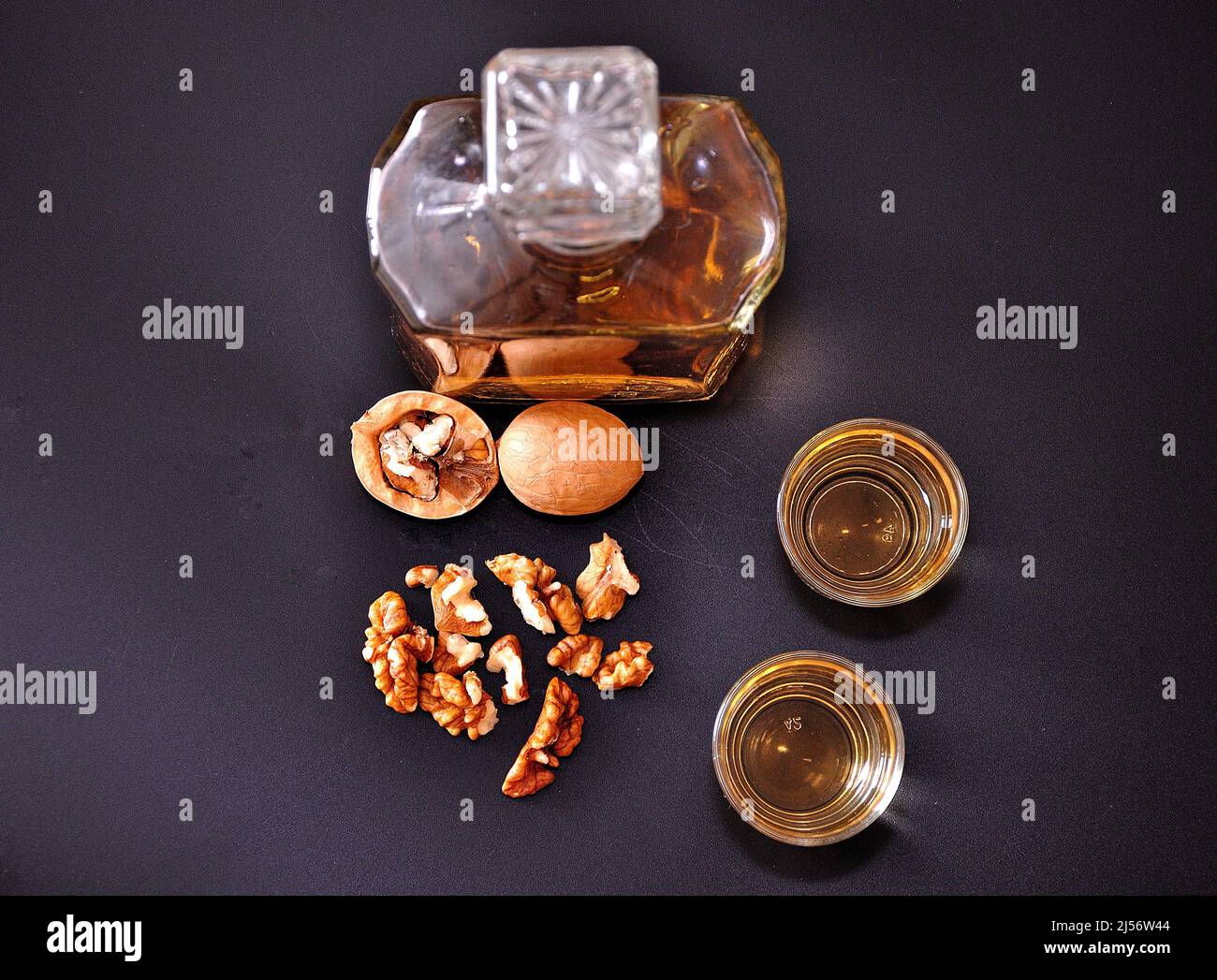 Walnut liqueur, strong homemade alcohol and cracked nuts on a black ...