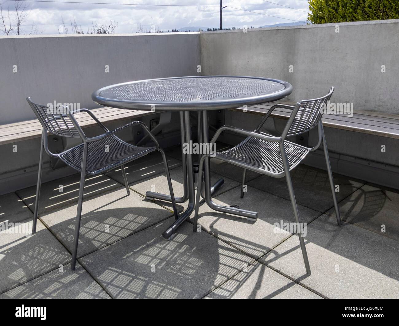 View of a rooftop balcony with a round, metal table and two chairs ...