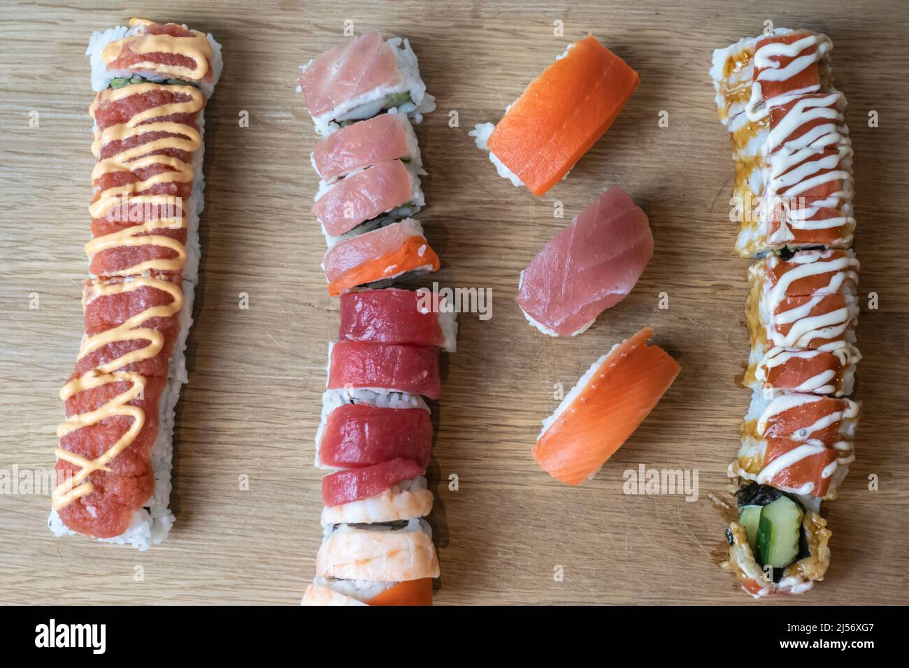 Wide, top down view of a variety of sushi rolls on a bamboo cutting ...