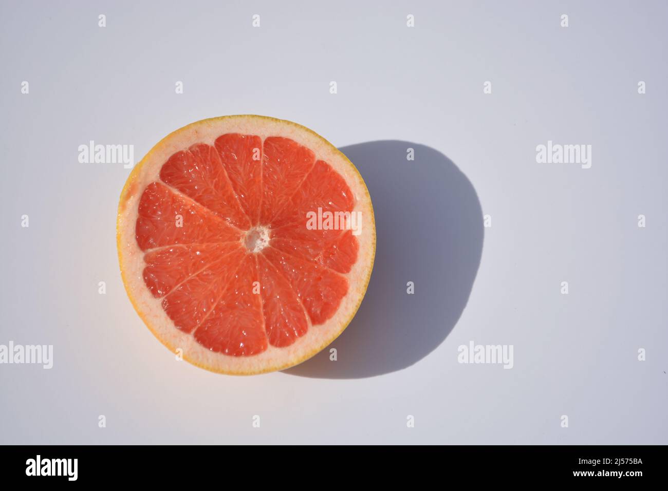 Grapefruit slice on white background with a strong shadow. Pink ...
