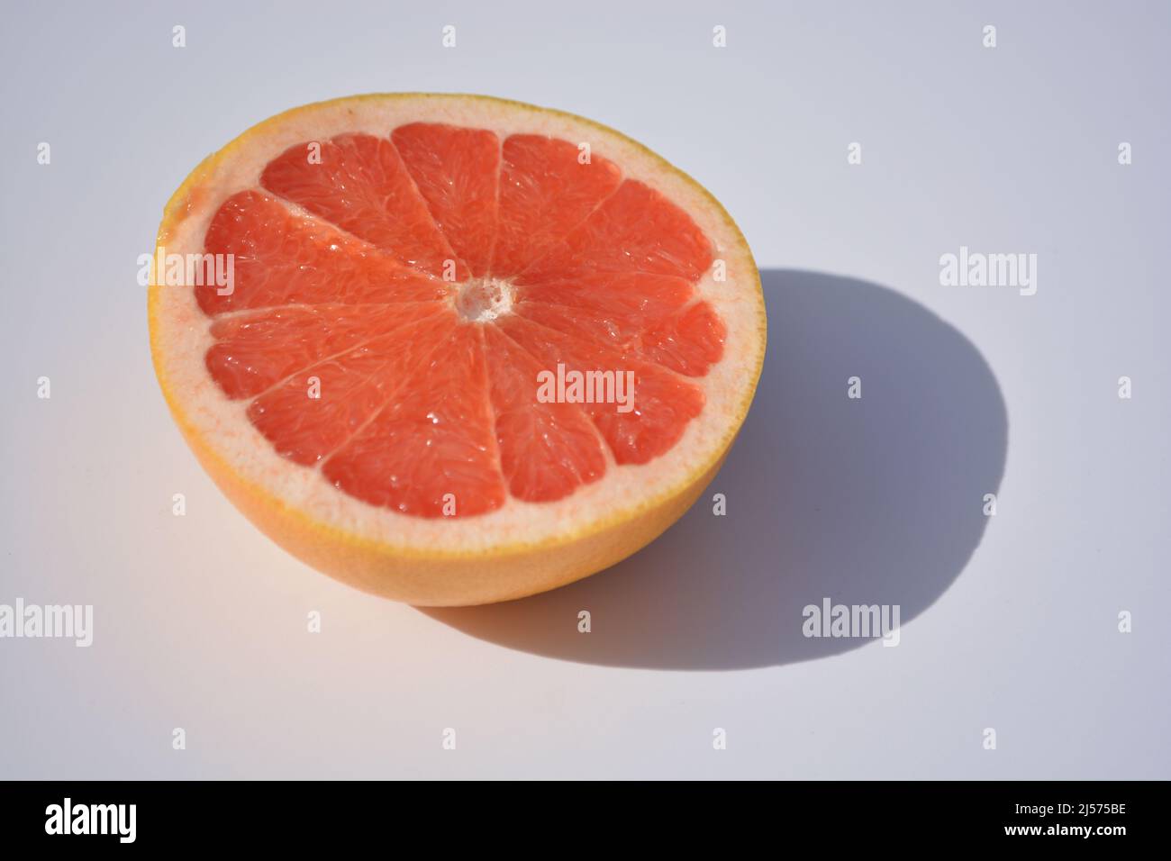 Grapefruit slice on white background with a strong shadow. Pink ...