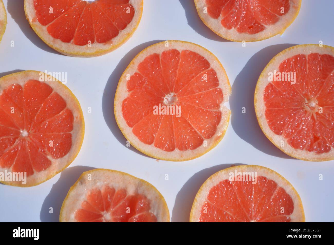 Colorful fruit pattern of fresh grapefruit slices on pink background ...