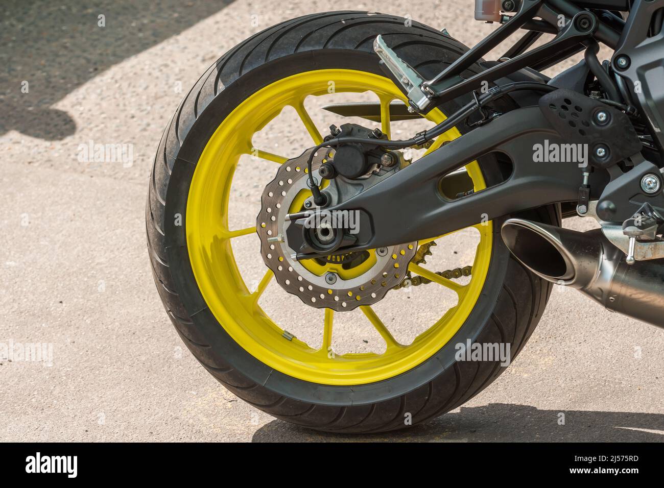 Wheel of a motorcycle with a yellow disk parked in the city, close-up ...