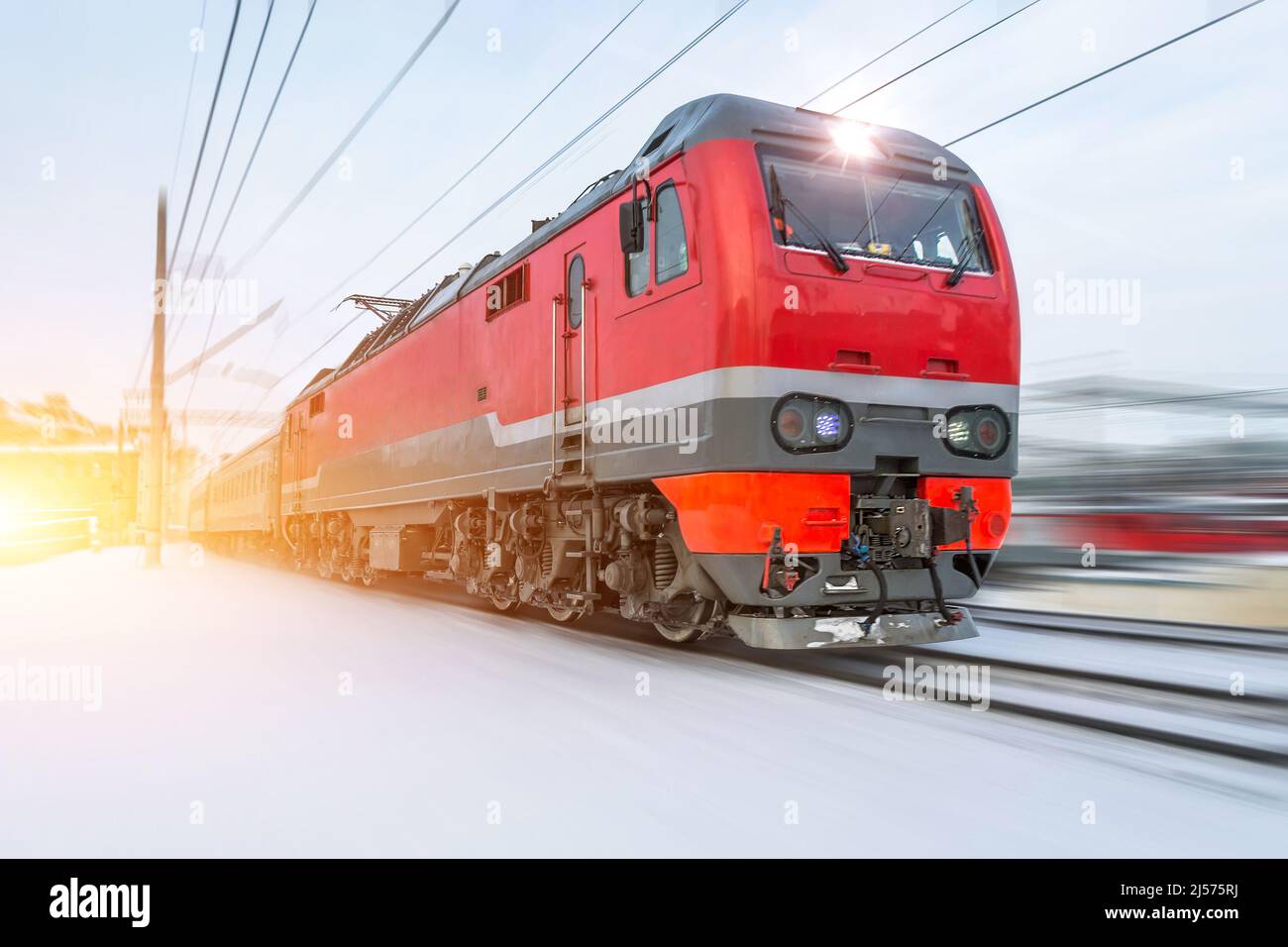High-speed red locomotive passenger train rides at high speed in winter ...