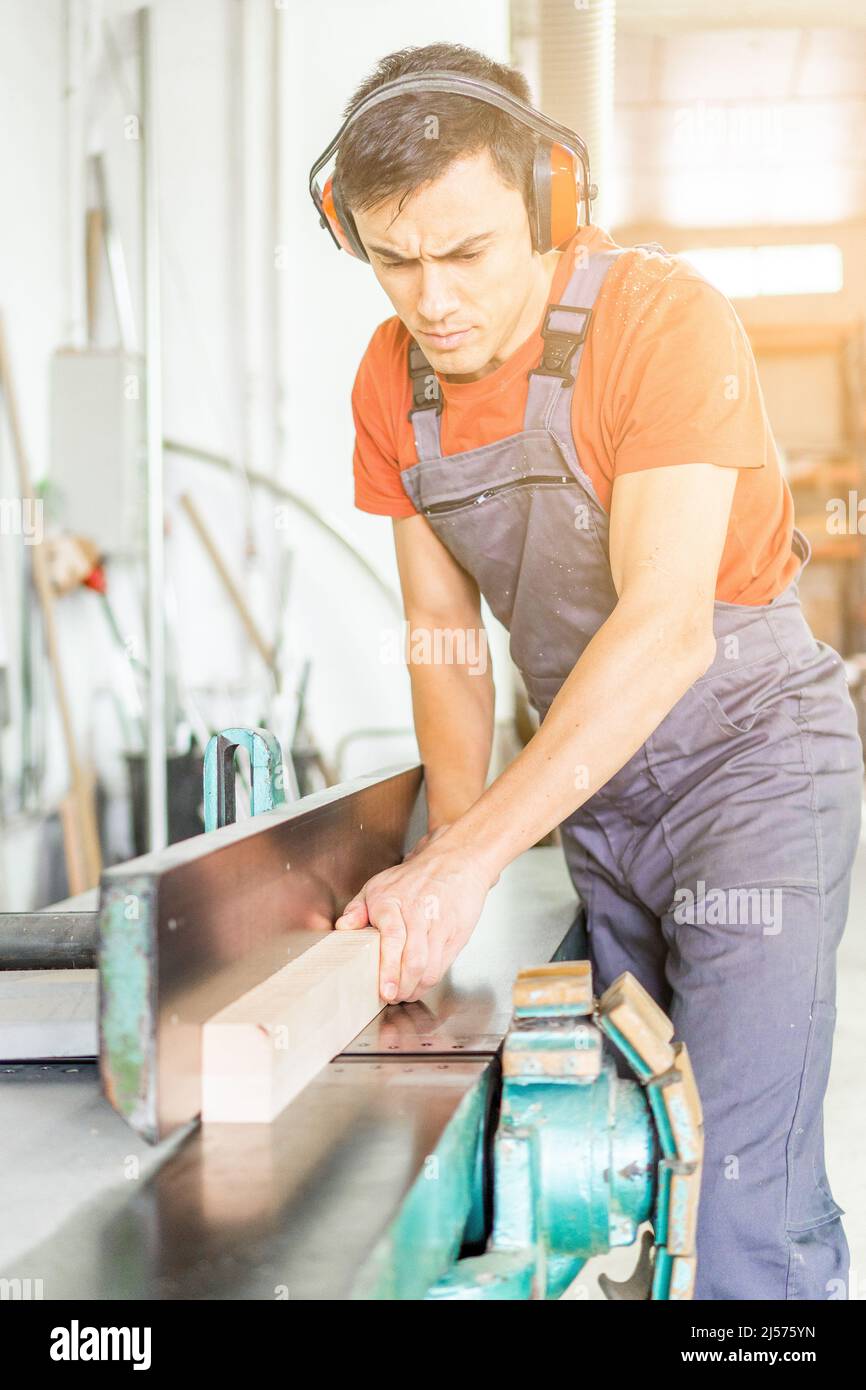 Concentrated woodworker trimming wooden plank in workshop Stock Photo ...