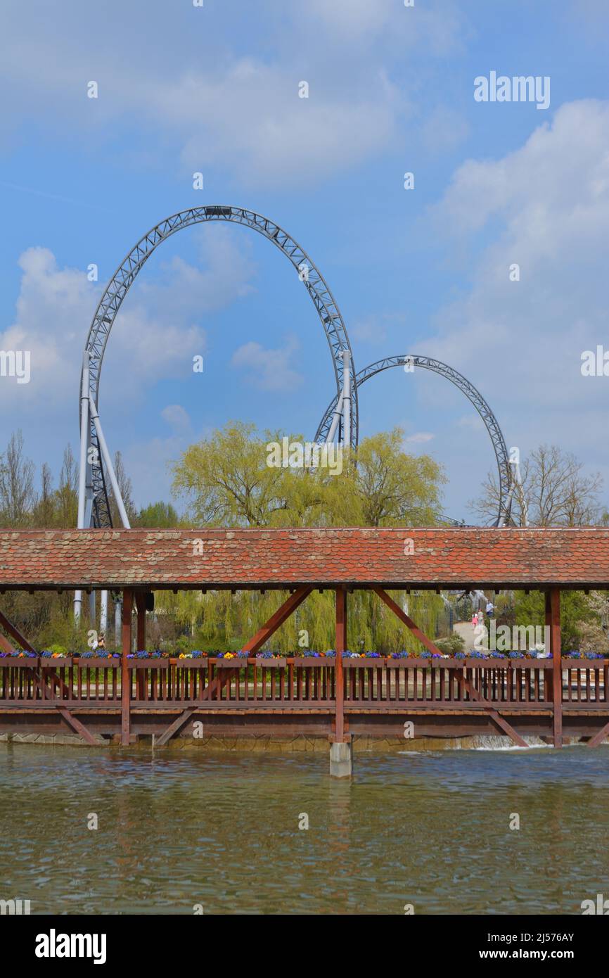 roller coaster with two loops in theme park behind a bridge in ...