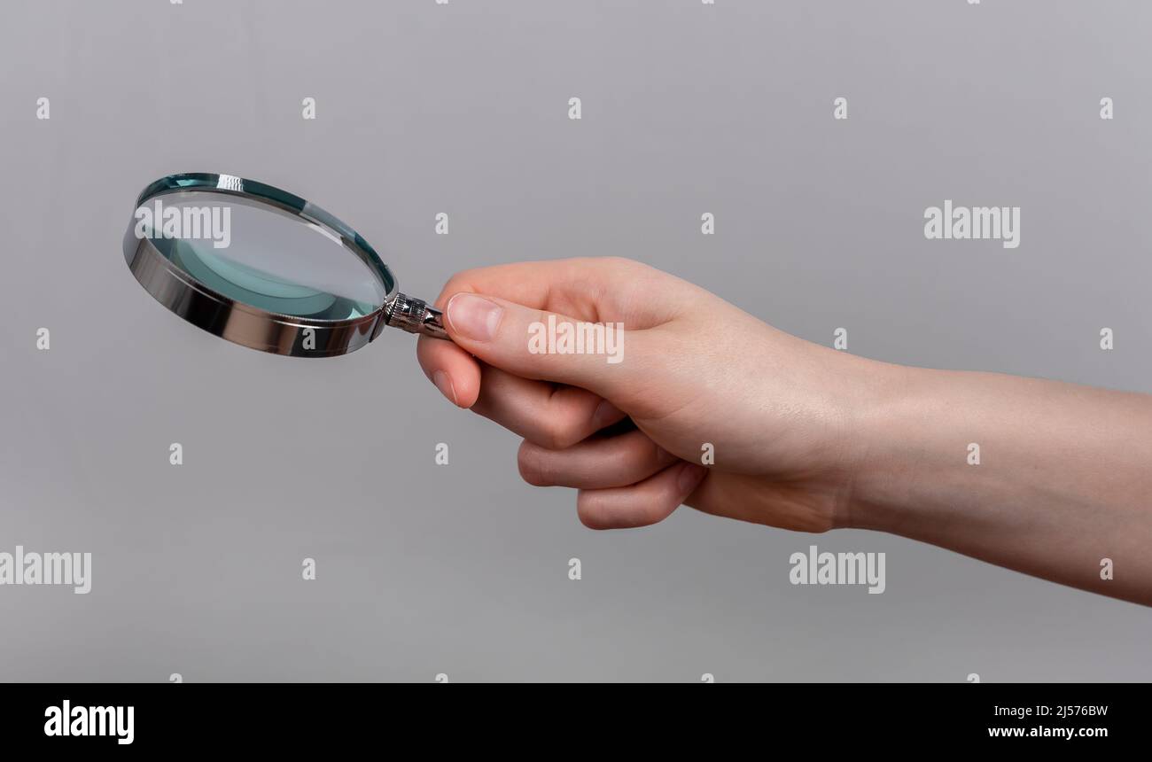 Woman hand holding magnifying glass. Data analysis, conducting research ...