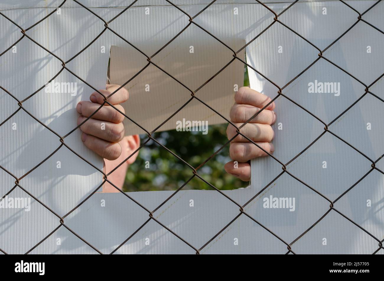 Two hands hold the banner attached to Chain-link fencing. Mature man ...