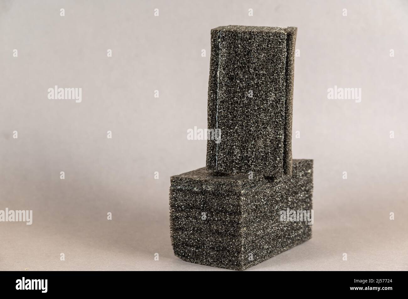 Minimalist geometric composition of pieces of black foam against a gray ...