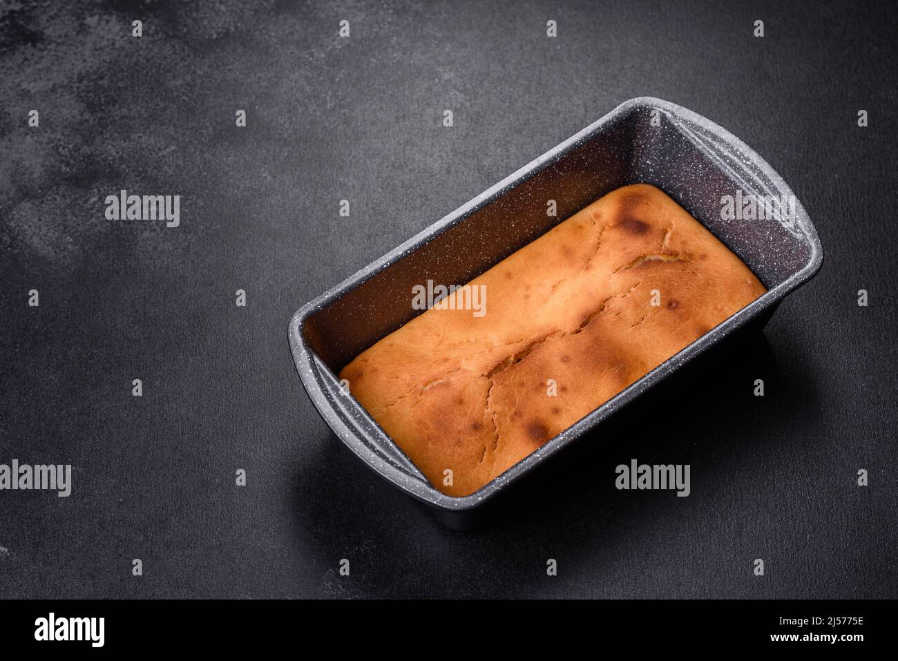 Baked rectangular cupcake with raisins and chocolate on a dark concrete ...