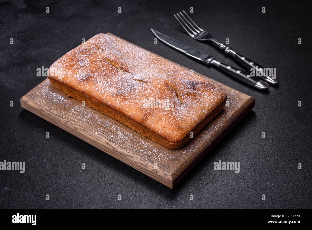 Baked rectangular cupcake with raisins and chocolate on a dark concrete ...