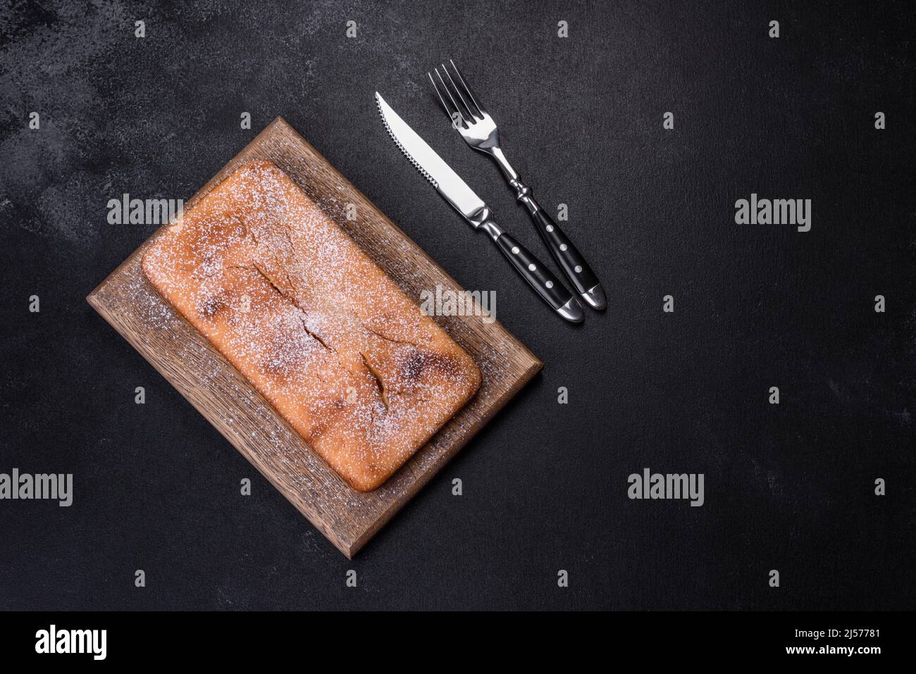 Baked rectangular cupcake with raisins and chocolate on a dark concrete ...
