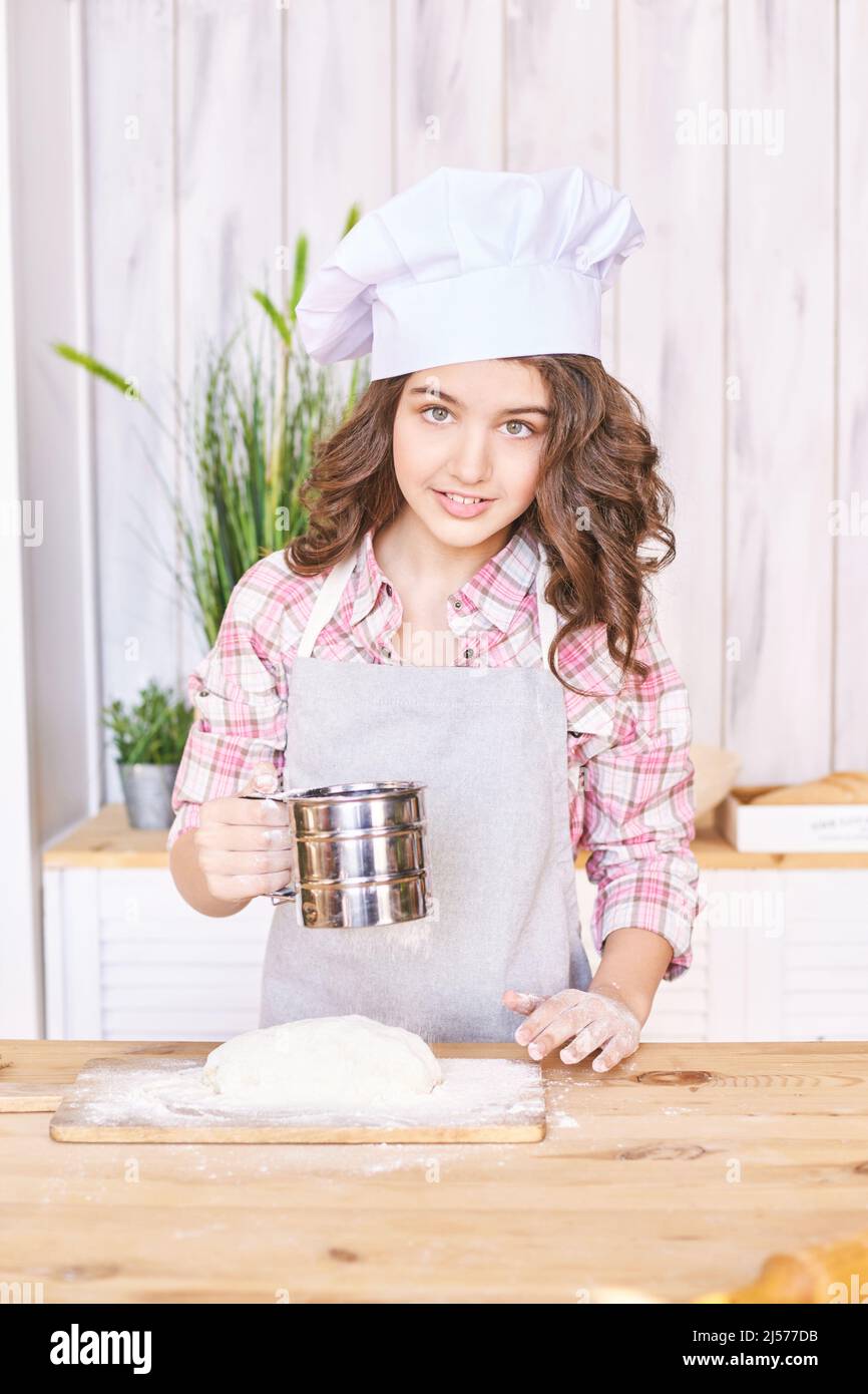 Young girl cooking at kitchen. Curly pretty child portrait. Chef ...