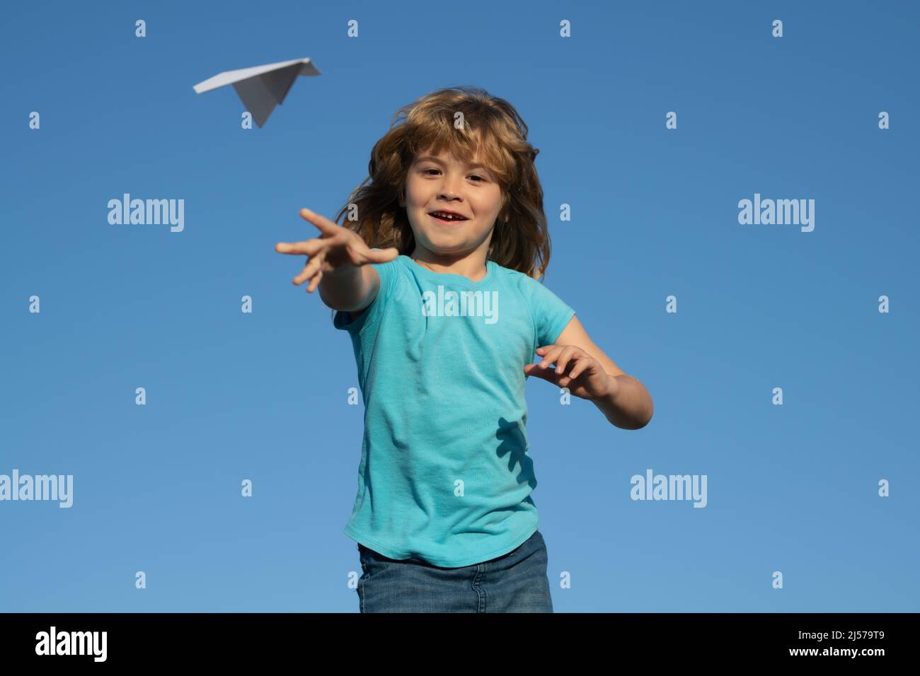 Boy child holding a paper airplane outdoor. Happy child playing with ...