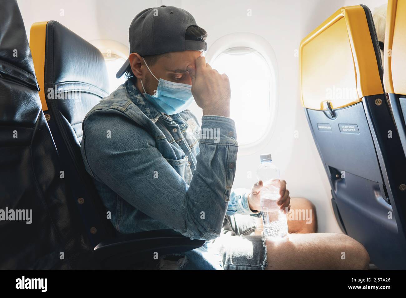 Young man traveler wearing prevention mask during a flight inside an ...