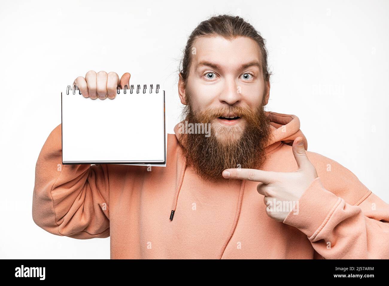 Scandinavian handsome happy man holding notepad and points to paper ...