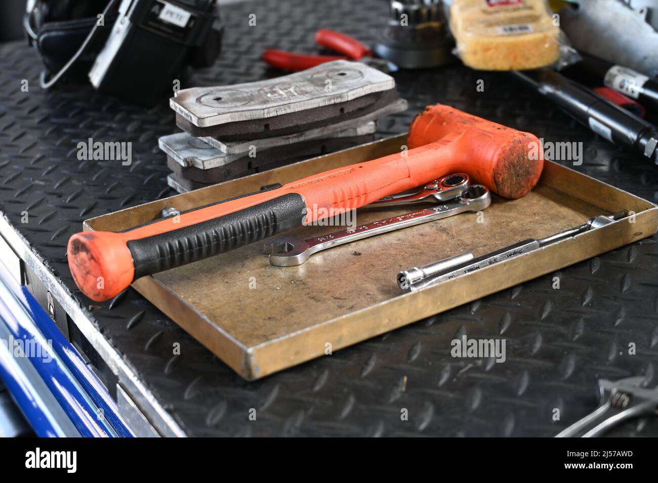 A workshop table with spanner’s and an orange hammer sitting on a tray ...