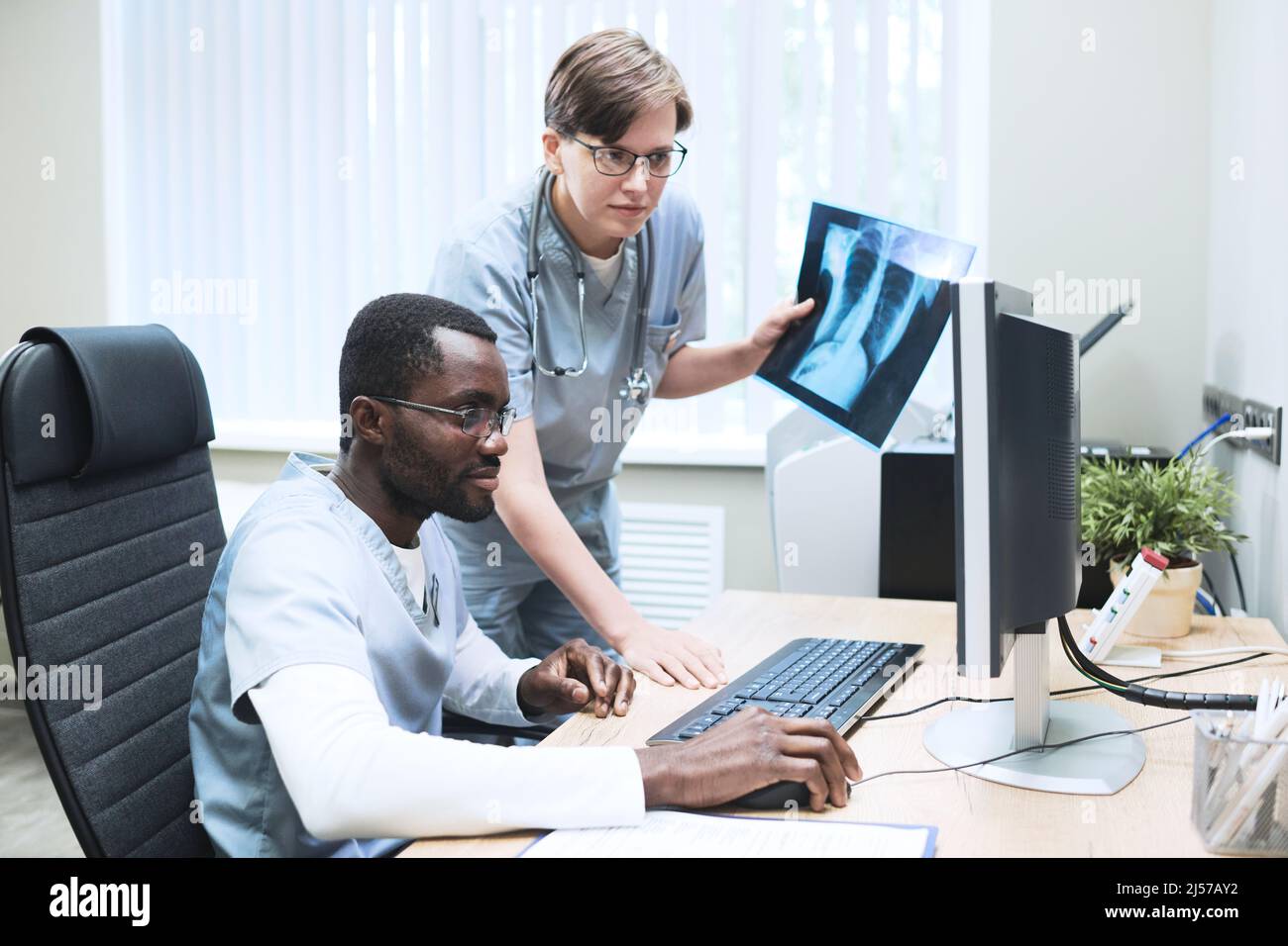 Young multi-ethnic medical specialists using computer while doing MRI ...