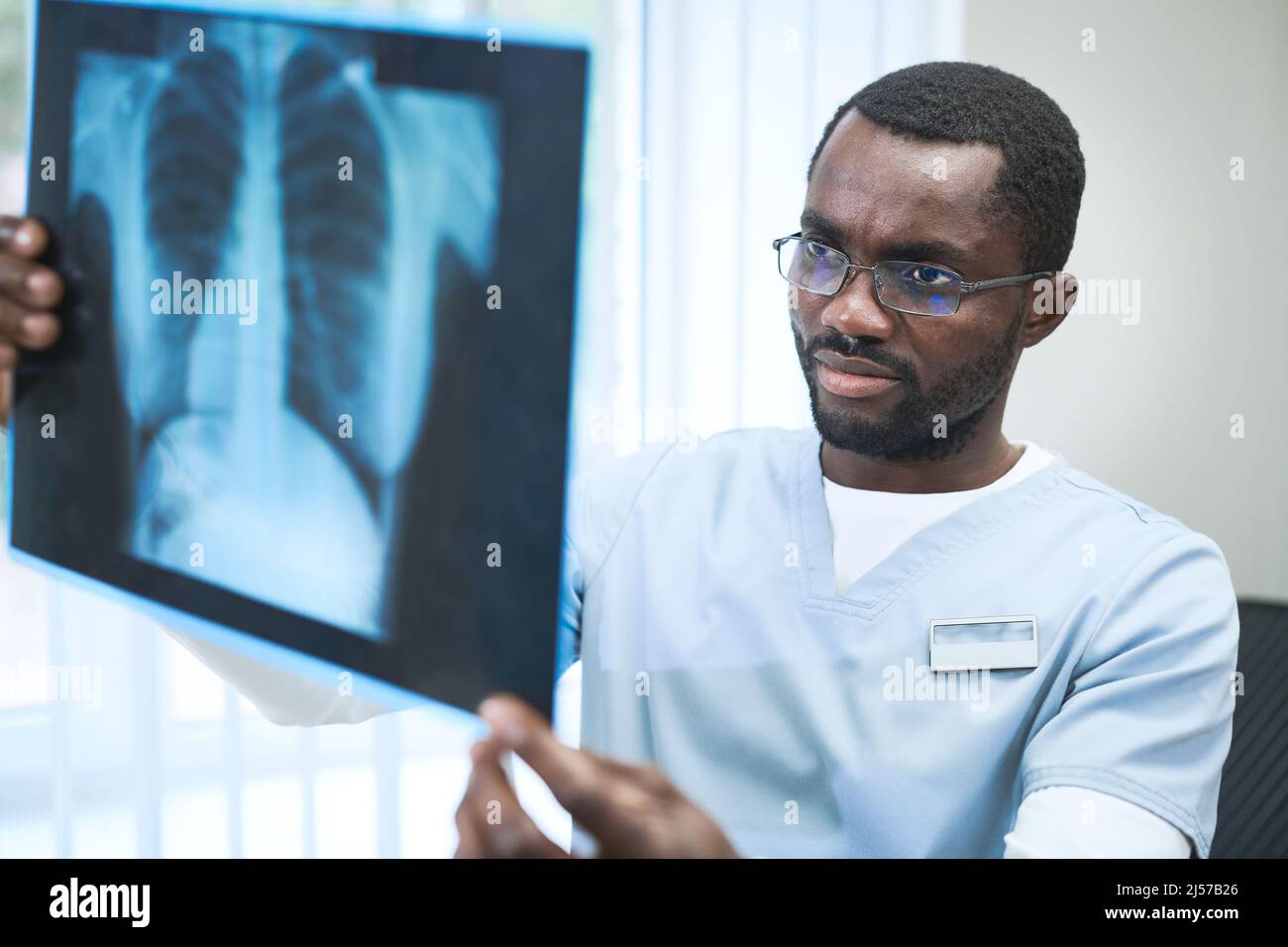 Concentrated young Afro-American doctor in eyeglasses and uniform ...