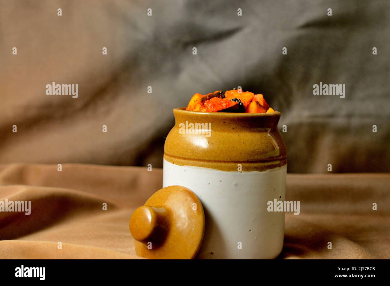 Homemade raw mango pickle in a traditional ceramic jar on Brown ...