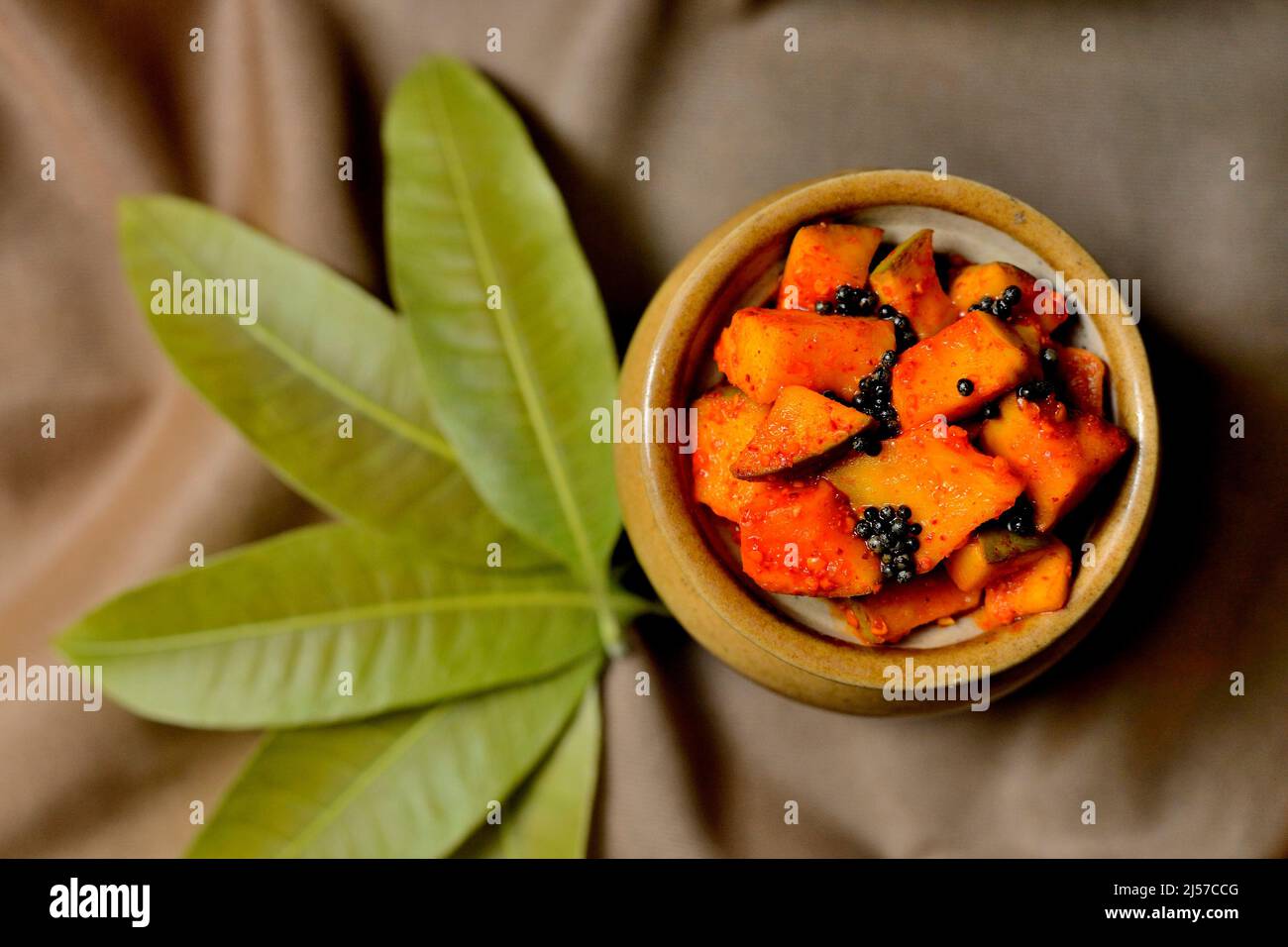 Homemade raw mango pickle in a traditional ceramic jar on Brown ...