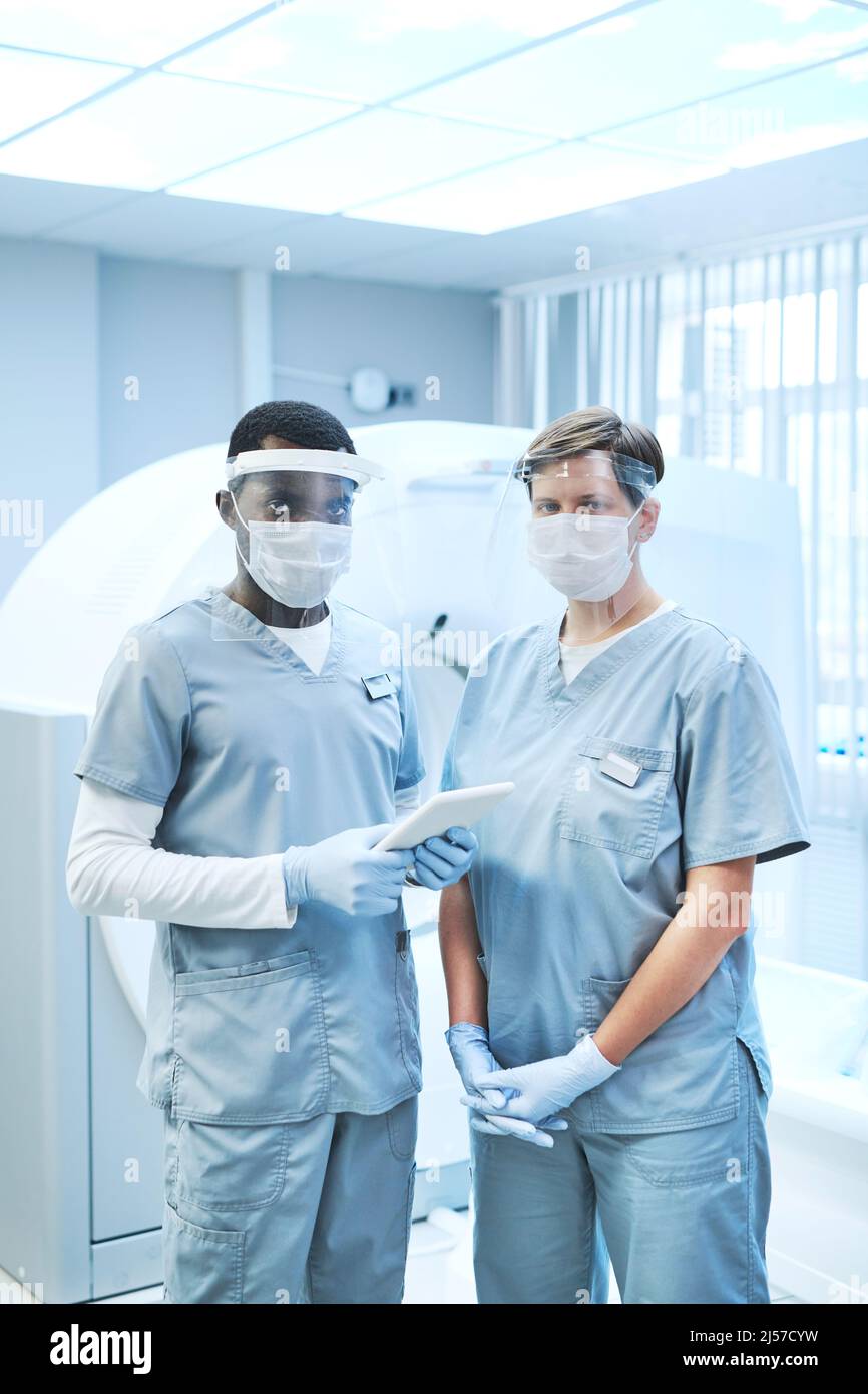 Portrait of interracial nurses in scrubs and protection shields ...